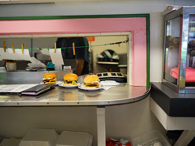 The pass-through window offers a glimpse of culinary magic – where burgers emerge transformed from humble ingredients into objects of desire.