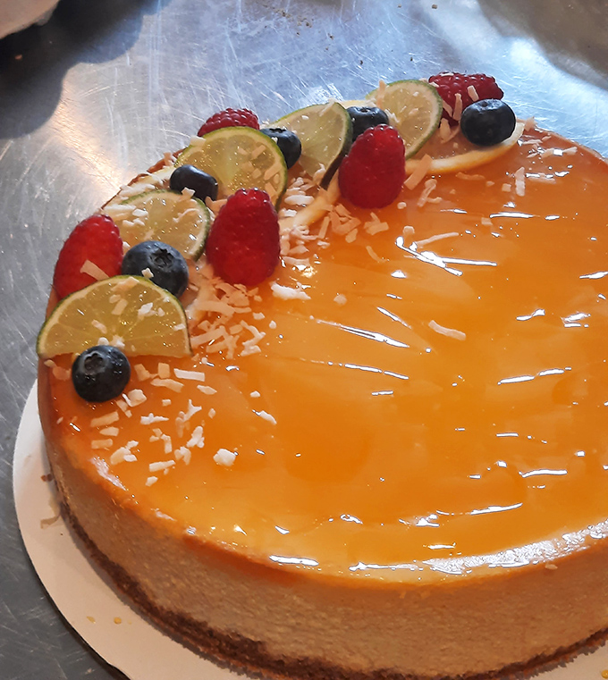 This mango cheesecake topped with fresh berries and lime is basically a tropical vacation without the TSA pat-down. The glossy finish catches light like a sunset over the ocean.