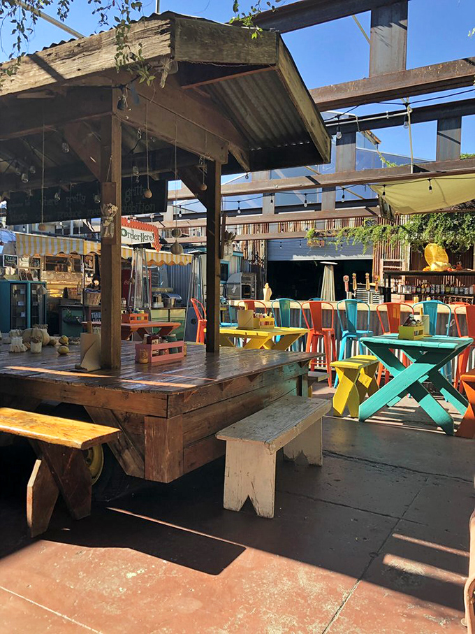 The outdoor dining space bursts with color against the desert sky. Those turquoise and yellow picnic tables practically demand you sit down and stay awhile.