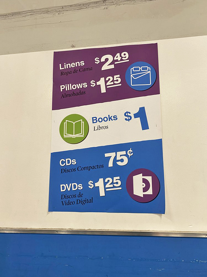 The pricing sign that explains why savvy shoppers get that gleam in their eyes. Books for a dollar and linens for $2.49? No wonder the parking lot is full.