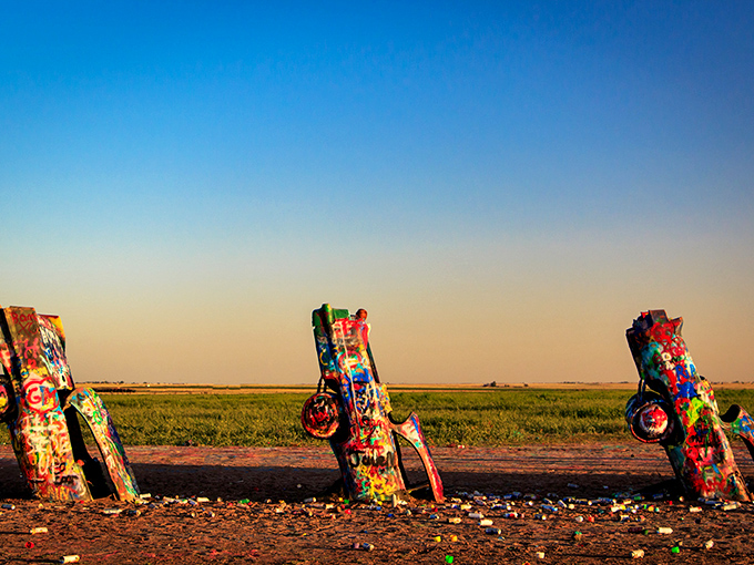 Sunset at Cadillac Ranch casts long shadows from these automotive monuments. The golden hour transforms these colorful relics into silhouetted sentinels.