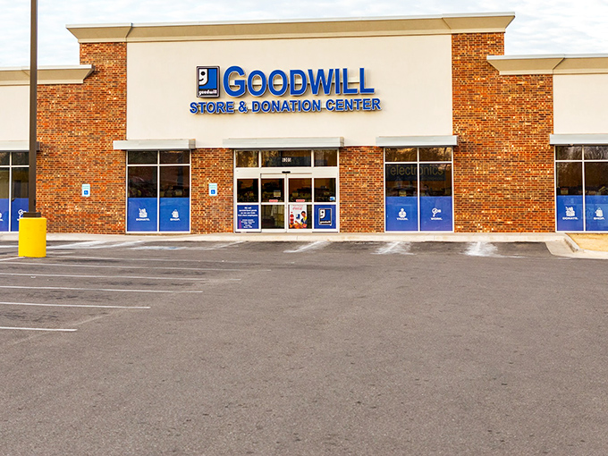 The bright blue Goodwill sign beckons like a lighthouse to bargain hunters. Shopping paradise awaits inside these brick walls!