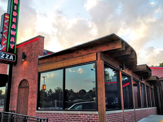 Hideaway Pizza's neon sign glows like a beacon for hungry souls. Brick walls and wooden beams promise comfort food memories in the making.