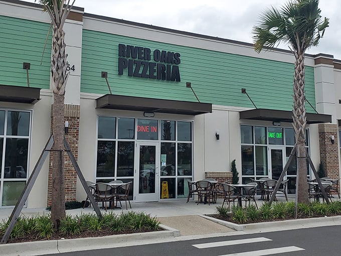 The inviting green exterior of River Oaks Pizzeria promises simple pleasures inside. Palm trees and patio seating add that perfect coastal touch.