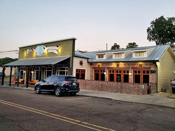 Twilight transforms this brick-and-wood riverfront grill into a beacon for steak lovers. String lights add that perfect touch of Mississippi magic!
