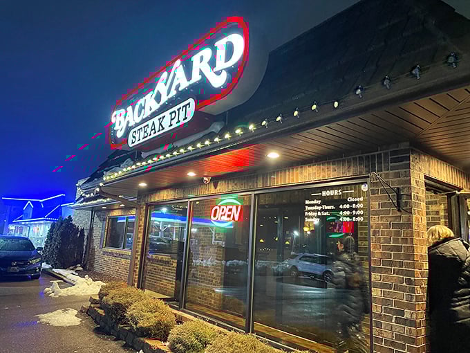 The Backyard Steak Pit's glowing sign is like a lighthouse for hungry travelers. Brick, warmth, and the promise of sizzling perfection await.