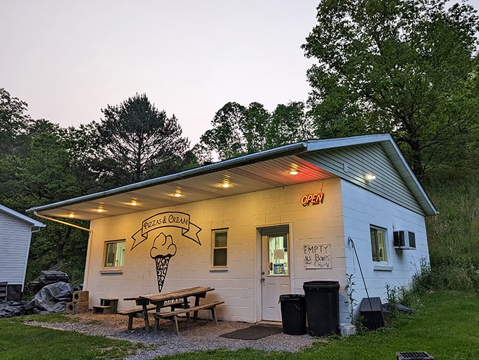 Evening glow illuminates this unassuming pizza haven, where picnic tables invite you to savor life's simple joys one slice at a time.