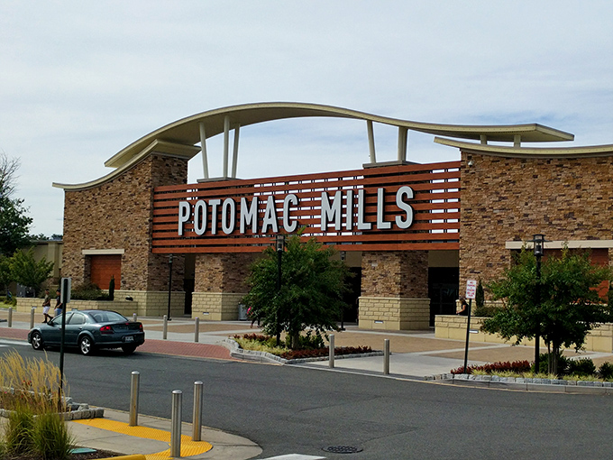 Potomac Mills stands proud against the sky, a shopping cathedral where credit cards come to worship. Those wooden slats hide a wonderland of discounts.