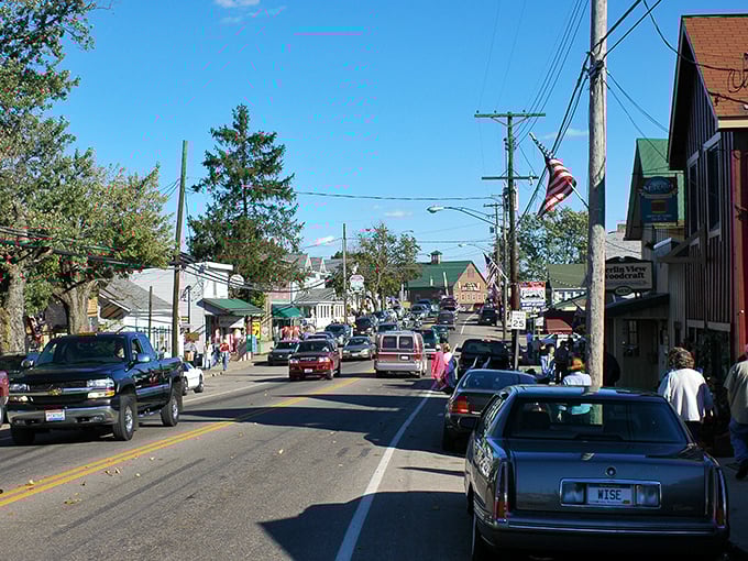 Main Street in Berlin, Ohio bustles with visitors exploring shops while modern vehicles share the road with occasional horse-drawn buggies.