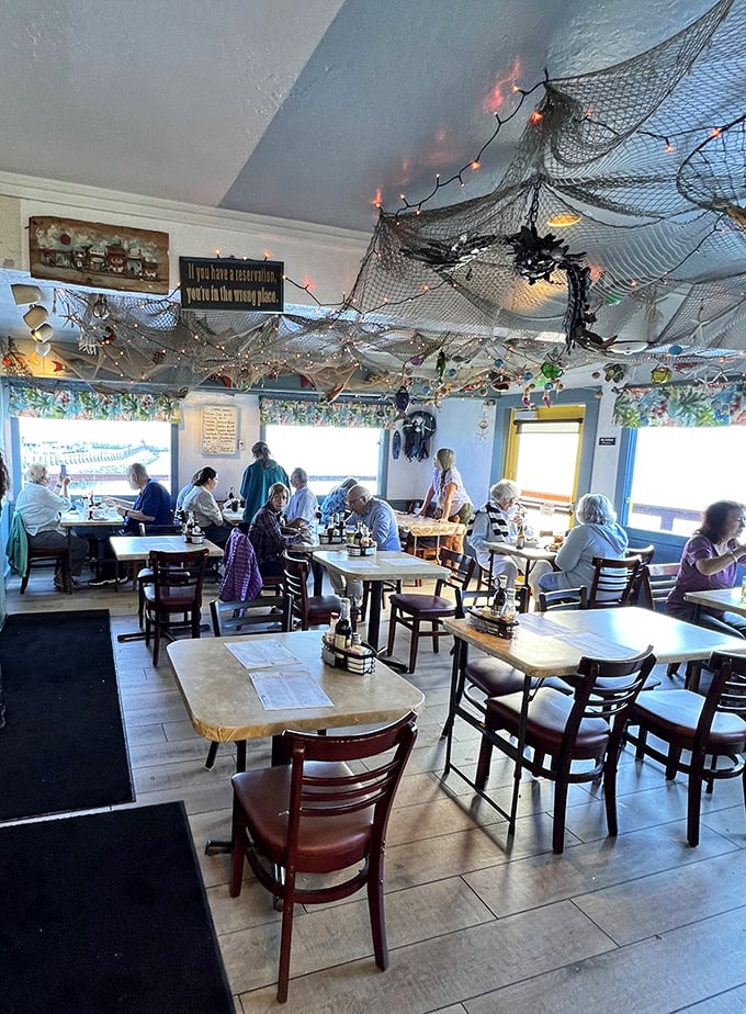 Fishing nets draped from the ceiling create a maritime wonderland, while the sign reminds you that reservations are for fancy places, not seafood sanctuaries like this.