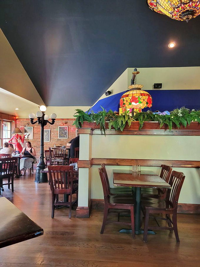 Tiffany-style lamps cast a warm glow over wooden tables while lush ferns create the perfect ambiance for comfort food revelations.