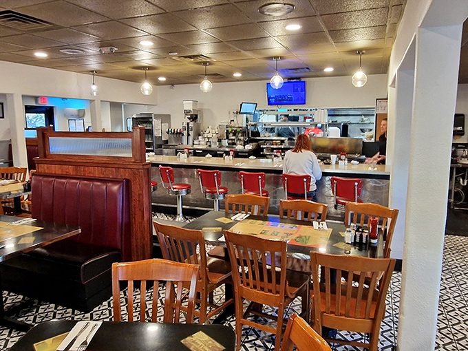 Classic diner aesthetics done right&mdash;red counter stools, wooden chairs, and that unmistakable pattern of black and white floor tiles that whispers "good food ahead."