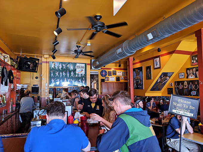 Inside, the mustard-yellow ceiling and pop culture memorabilia create a playful atmosphere where serious hot dog business happens daily.