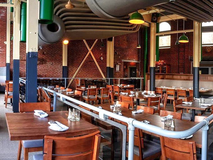 Industrial chic meets comfort in this dining room where exposed brick and overhead pipes create atmosphere without sacrificing warmth.
