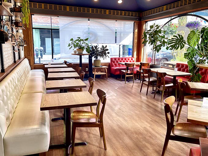 Plants thrive alongside conversations in this sunlit sanctuary. The red chairs and cream banquettes aren't just furniture&mdash;they're invitations to linger over one more coffee.