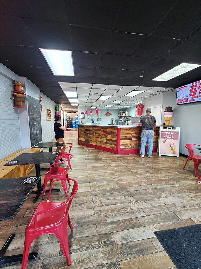 Inside, reclaimed wood meets modern minimalism. The red chairs pop against wooden floors like cherries on vanilla, creating the perfect stage for custard contemplation.