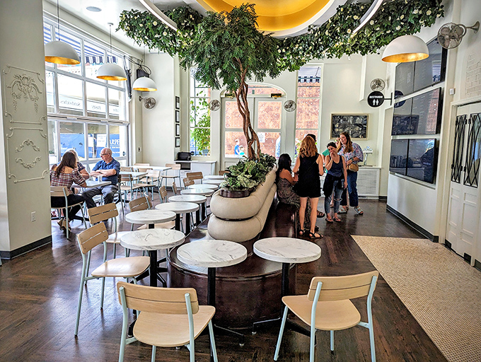 The interior's centerpiece tree brings the outdoors in, creating a garden-like oasis where conversations bloom as naturally as the greenery overhead.