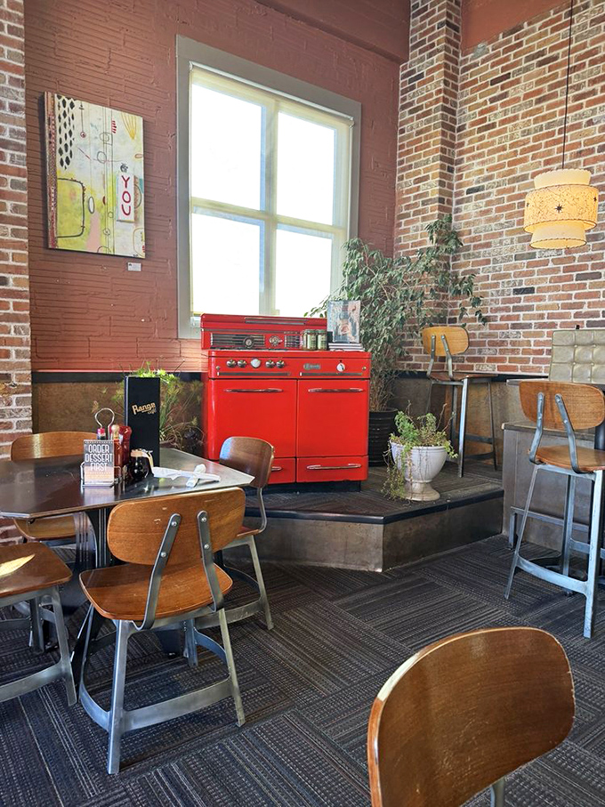 Vintage meets whimsy in this corner of Range Cafe, where a cherry-red retro stove stands sentinel among exposed brick walls and warm wooden furnishings.