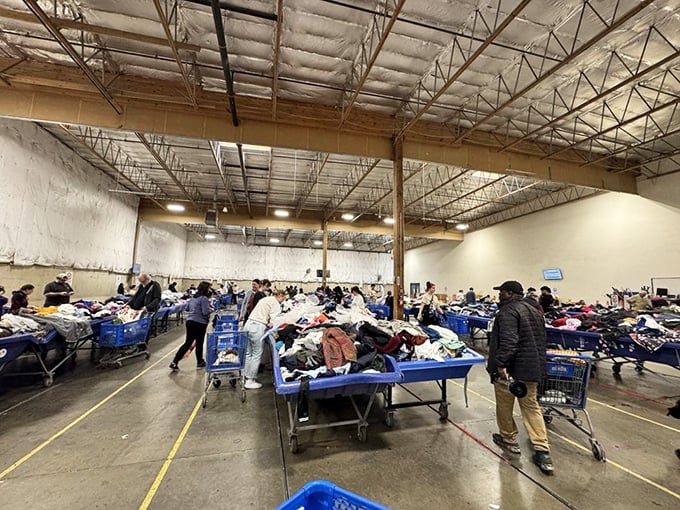 Treasure hunters navigate the sea of blue bins, each cart a vessel on an expedition for that perfect find nobody else spotted.