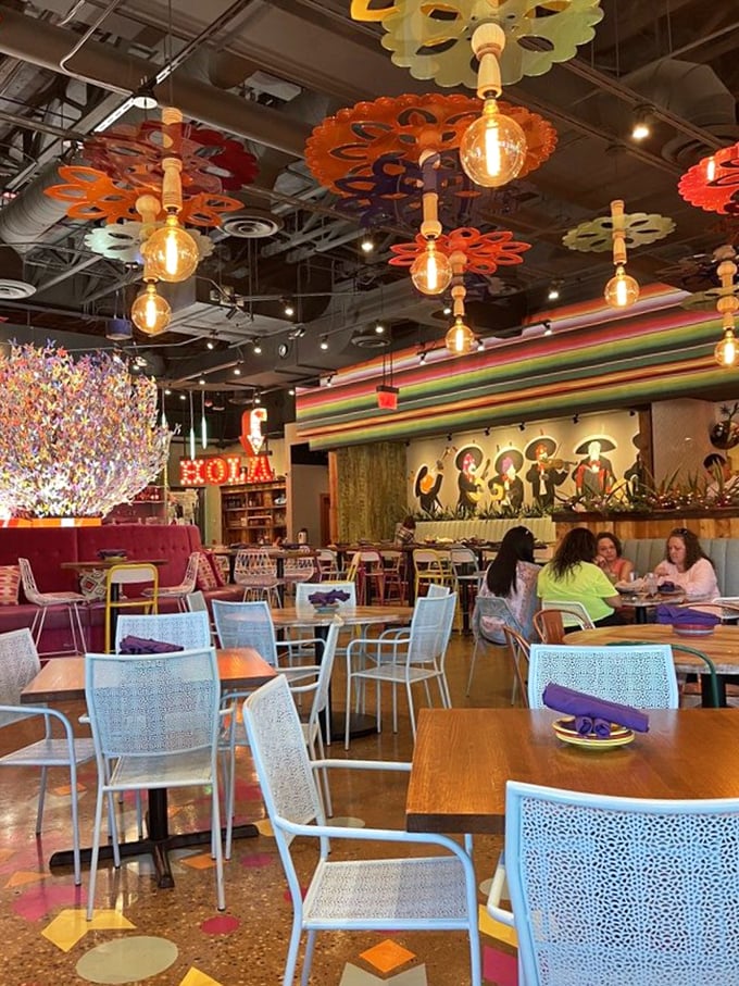 Colorful flower-shaped light fixtures dance overhead while the "HOLA" sign glows with the warmth of a thousand welcomes.