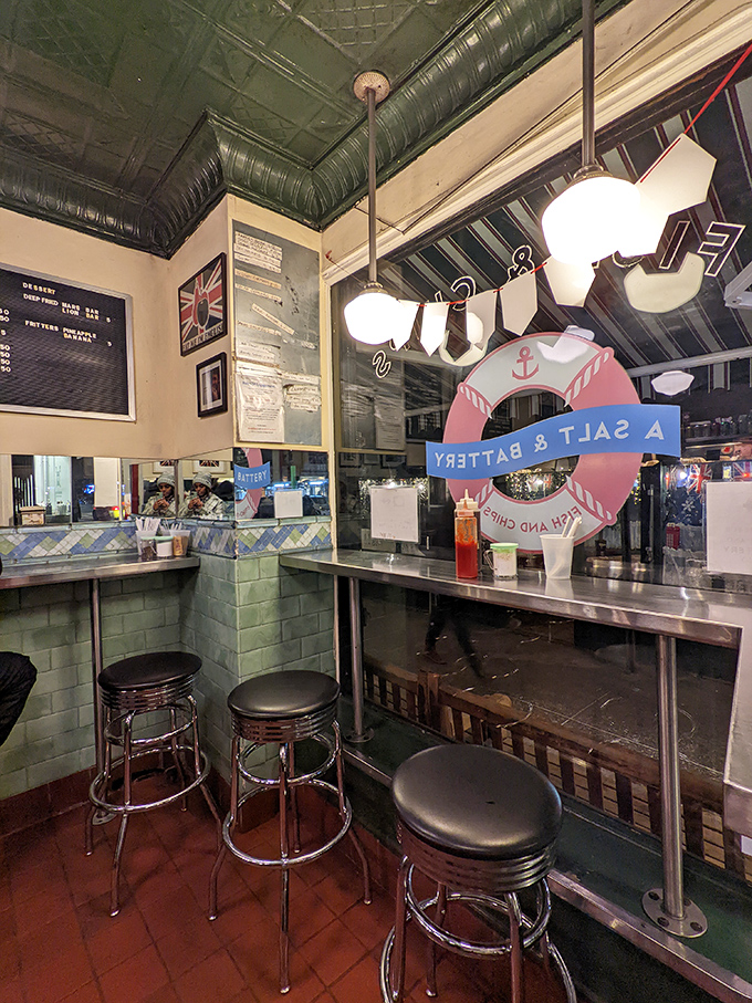 Nautical charm meets no-nonsense dining. The mint-green tiled walls, chrome bar stools, and life preserver create an authentic chippy atmosphere where the food takes center stage.