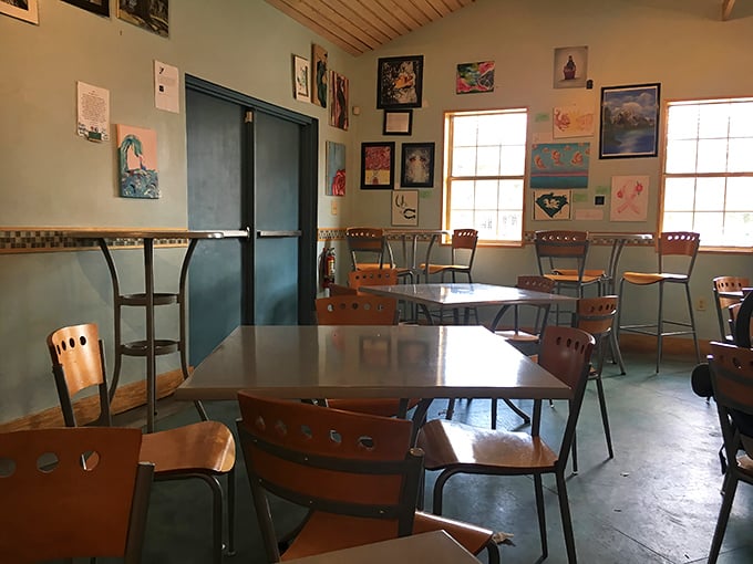 Local artwork adorns mint-green walls while wooden ceiling beams add rustic charm to this cozy space where culinary magic happens daily.