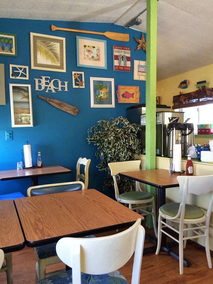 Beach vibes meet comfort food inside this cheerful space. The bright blue accent wall adorned with coastal art sets the perfect backdrop for serious biscuit business.