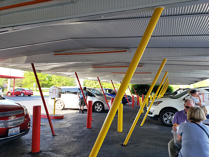 Under this canopy of nostalgia, cars gather like faithful pilgrims at a shrine to American comfort food. No apps needed&mdash;just push the button and feast.