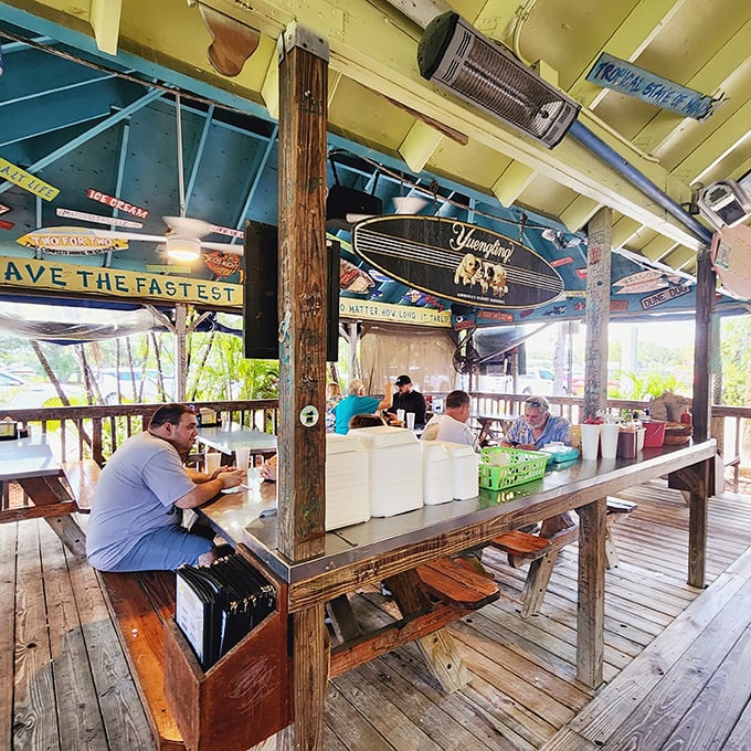 Surfboards hanging from weathered wooden beams tell stories of ocean adventures while diners enjoy the open-air experience beneath them.