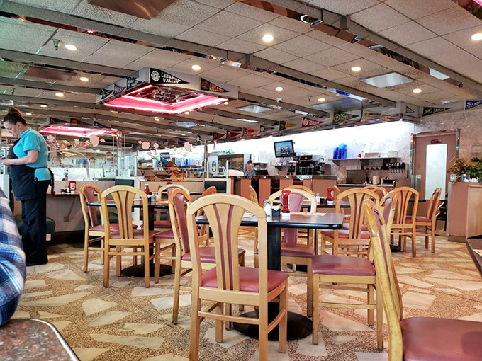 Classic diner ambiance with wooden chairs, terrazzo floors, and that unmistakable neon glow&mdash;where conversations flow as freely as the coffee refills.