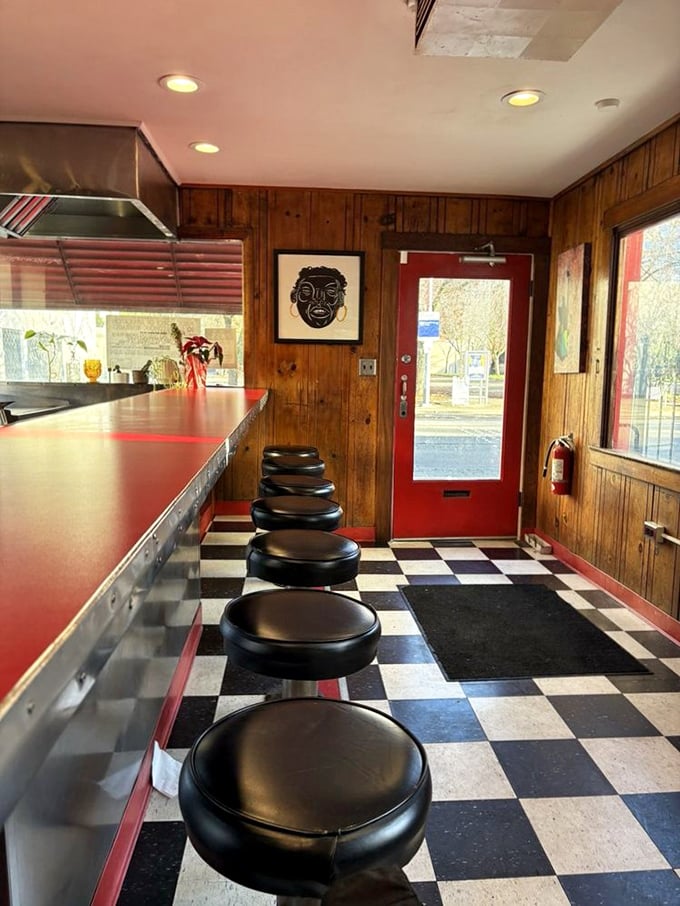 Classic black and white checkered floors meet cherry-red countertops in this time capsule where every stool tells a story.