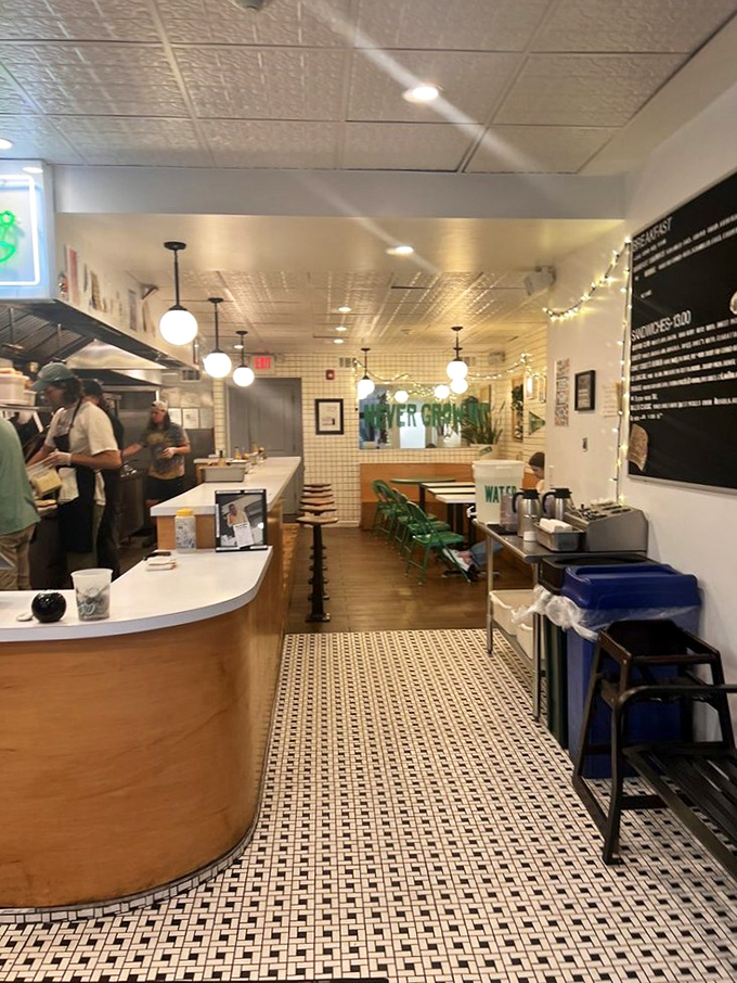 Inside, minimalist design meets maximum flavor. White tiles, wooden counters, and those signature green chairs create a space where the food becomes the star.