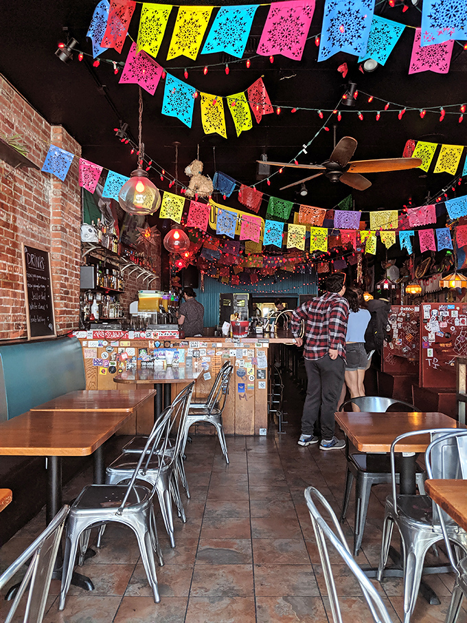 Papel picado flags create a perpetual fiesta overhead while exposed brick walls ground the space in urban cool. This isn't decoration&mdash;it's a mood.