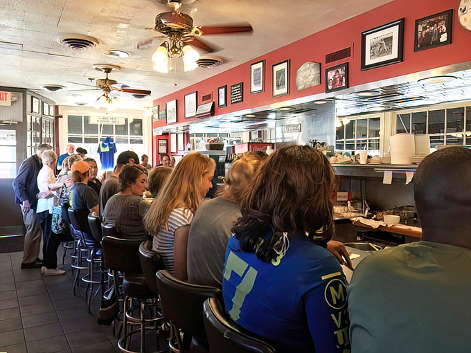 Counter seating isn't just practical&mdash;it's theater with a front-row view of breakfast artistry in action. The red walls and ceiling fans create classic diner ambiance.