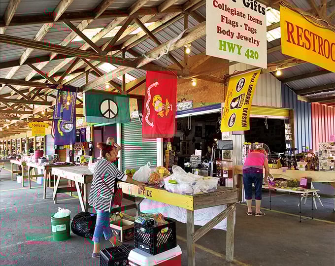 Colorful flags hang overhead as shoppers browse produce and merchandise. The market's indoor sections offer everything from collegiate gear to fresh vegetables.