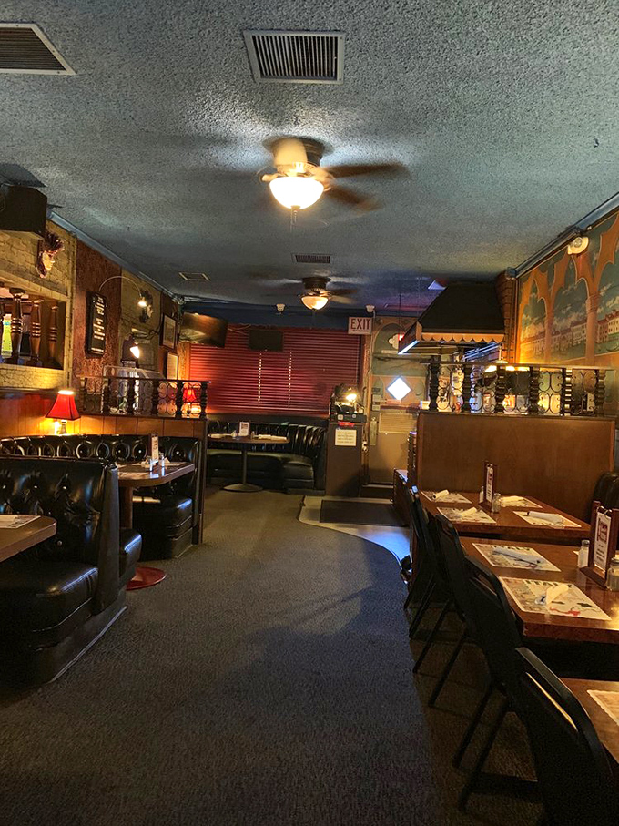 Step inside and let your eyes adjust to the perfect dive bar darkness where ceiling fans lazily spin above leather booths that have witnessed decades of celebrations and confessions.