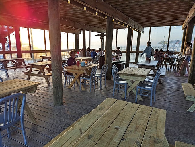 Golden hour transforms this simple deck into dining theater. The wooden tables might be basic, but that sunset view is five-star luxury without the pretense.