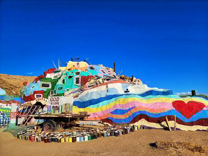 A kaleidoscope of colors erupts from the desert floor at Salvation Mountain, where "God is Love" shines under the blue sky.