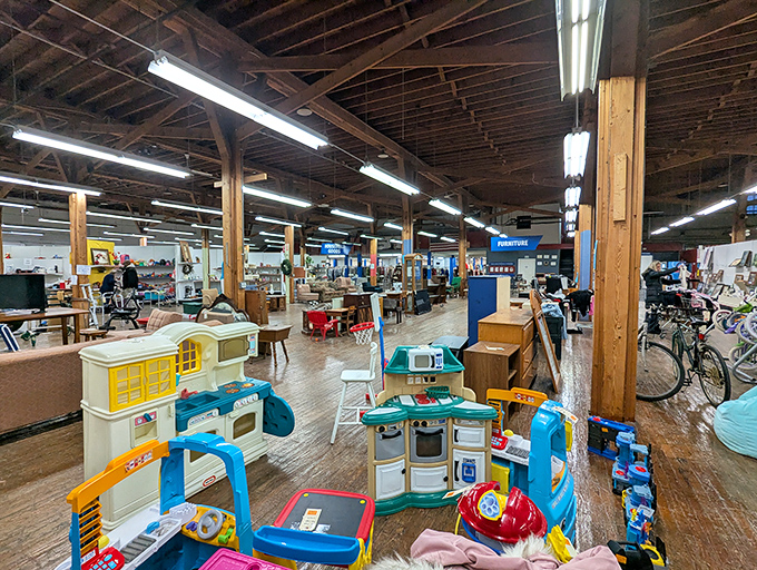 A wonderland of possibility unfolds under exposed wooden beams, where children's play kitchens neighbor vintage furniture in perfect thrift harmony.