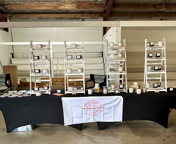 Artisanal candles meticulously displayed on white shelving. Each jar contains not just wax, but someone's handcrafted passion for fragrance.