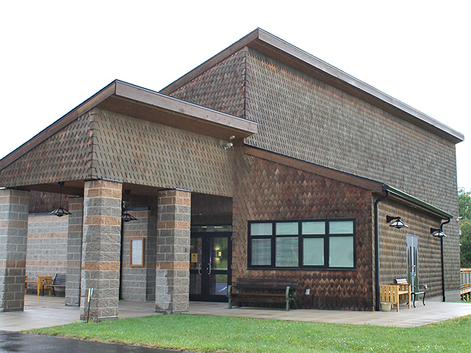 The education center's rustic architecture blends harmoniously with its surroundings, like a cozy library built by nature enthusiasts with excellent taste.