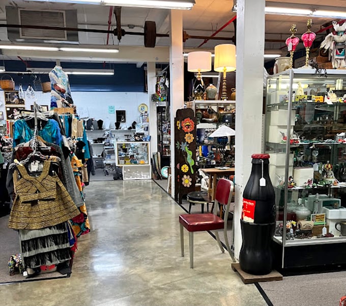 Vintage clothing hangs alongside glass display cases, while a giant Coca-Cola bottle stands sentinel in this corridor of collectibles.