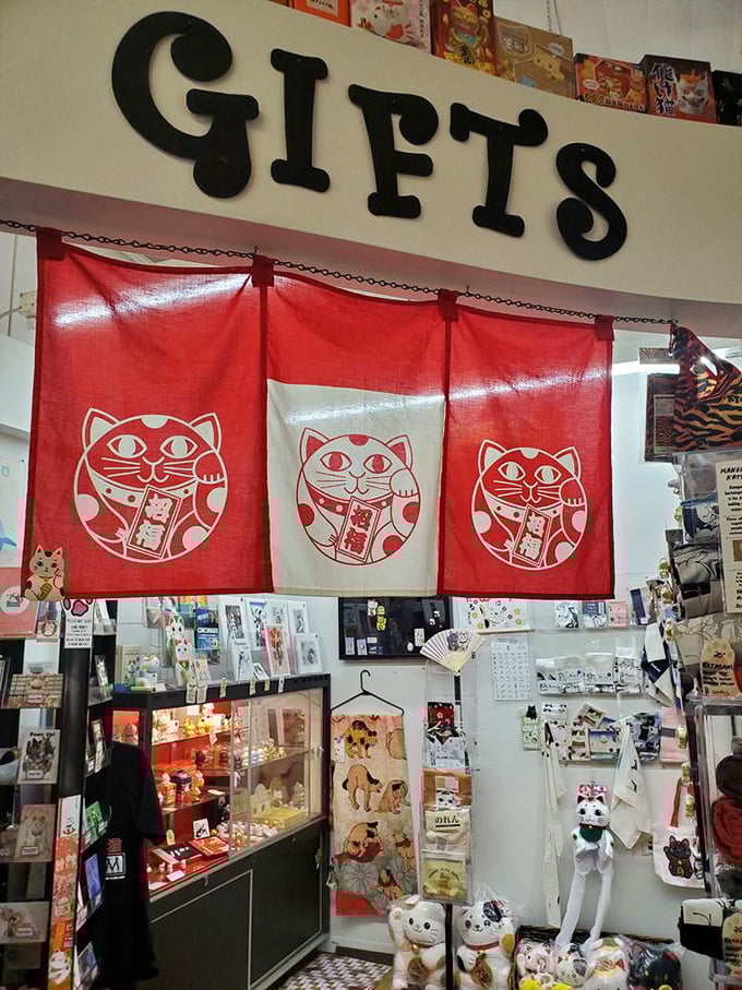 Red banners featuring the iconic Maneki Neko welcome visitors to the gift section, where you can adopt your own fortune-bringing feline friend.