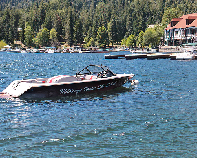A water ski boat waits patiently on the sapphire waters, ready to transform ordinary visitors into temporary daredevils with windswept hair.