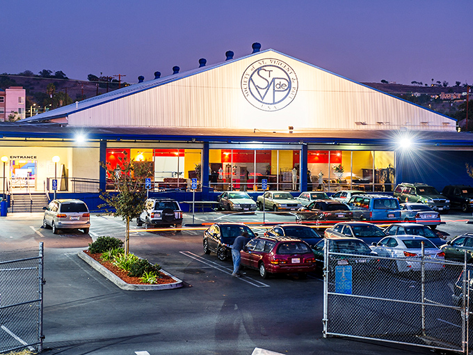 Night falls but the thrifting never stops at this illuminated bargain paradise. Cars gather like moths to a secondhand flame.