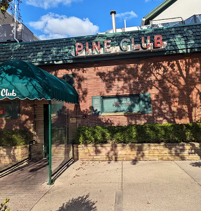 The Pine Club: Brick facade, vintage signage, and a green awning that whispers, "We were serving perfect steaks when your parents were dating."