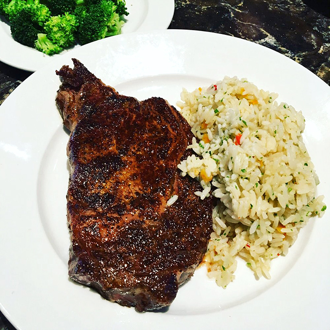 This 12oz ribeye doesn't just sit on the plate&mdash;it commands attention with its perfect char and juicy interior, flanked by rice pilaf and broccoli for those with a conscience.