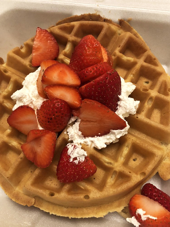 Behold the golden masterpiece: fresh strawberries and whipped cream crowning a perfectly crispy Belgian waffle treasure.