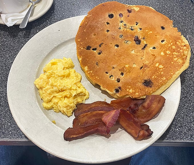 This isn't just any pancake&mdash;it's a blueberry-studded canvas of breakfast perfection paired with perfectly scrambled eggs and bacon for the complete morning symphony.