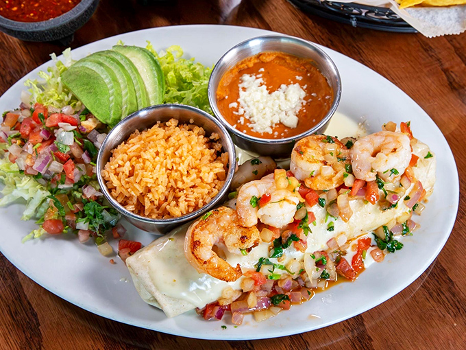 The Burrito Del Mar arrives like an edible work of art – succulent shrimp nestled in melted cheese with fresh avocado and pico de gallo standing guard.